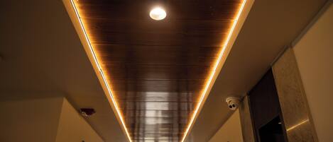Corredor com teto de madeira e iluminação embutida.