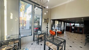Um interior moderno com divisória de vidro, área de jantar com cadeiras laranja e bancada de cozinha.