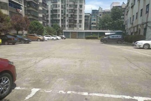 Um estacionamento com vários carros, ladeado por edifícios residenciais altos.