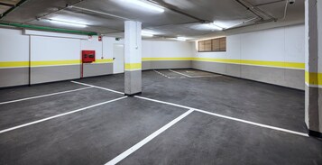 Garagem de estacionamento vazia com paredes brancas, listras amarelas e brancas e piso de concreto.