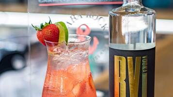 Uma garrafa de vodka BVI e um copo de cocktail com morangos e limão.