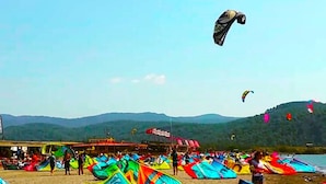 Uma praia com muitos velejadores coloridos e tendas montadas.