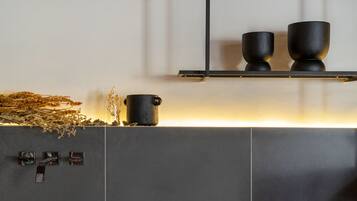 Uma casa de banho moderna com uma banheira independente, um porta-toalhas e uma estante com ramos decorativos e dois recipientes pretos.