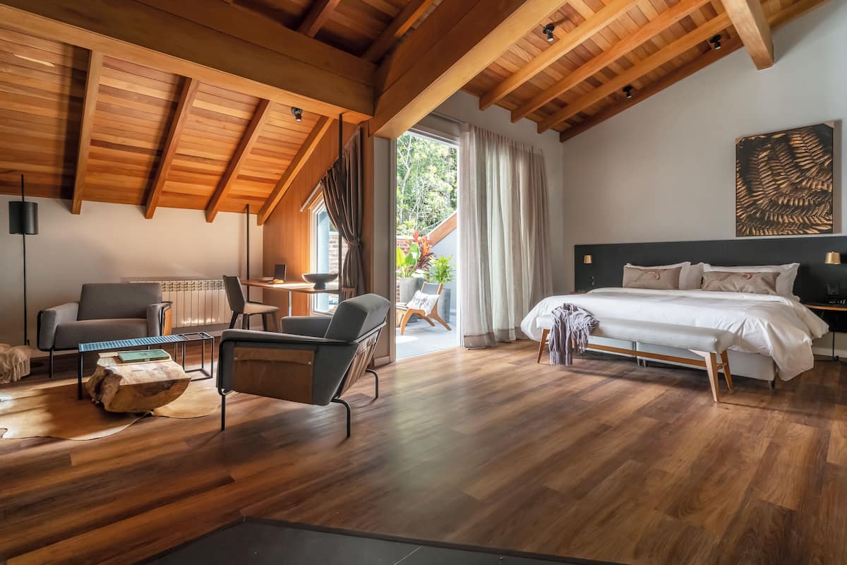 Um quarto com teto de madeira, uma cama, uma escrivaninha e uma cadeira.