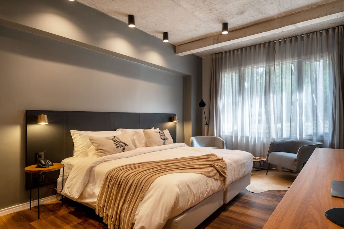 Quarto de hotel moderno com uma cama grande, uma escrivaninha e uma cadeira.
