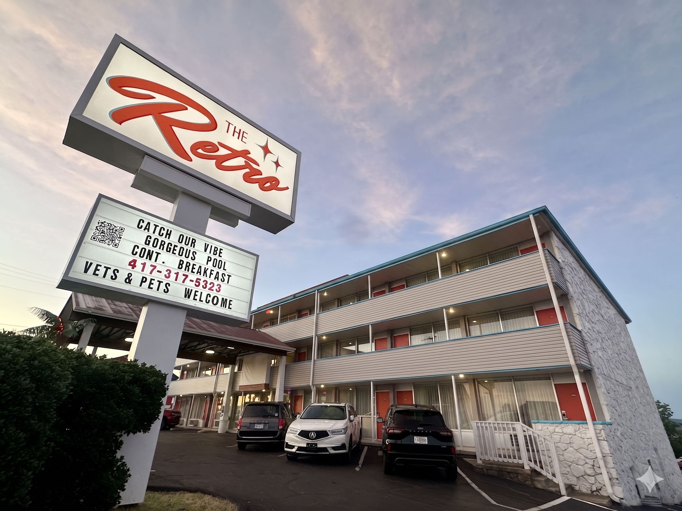 Um motel com letreiro retrô, piscina e espaço para café da manhã.