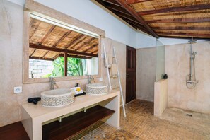 Casa de banho com duas pias, espelho, chuveiro e escada.