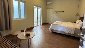 Quarto espaçoso com cama, área de estar com mesa e uma janela grande.