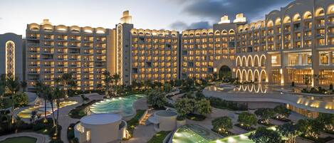 Um hotel grande com vários andares, um pátio central com piscina e áreas ajardinadas ao redor.
