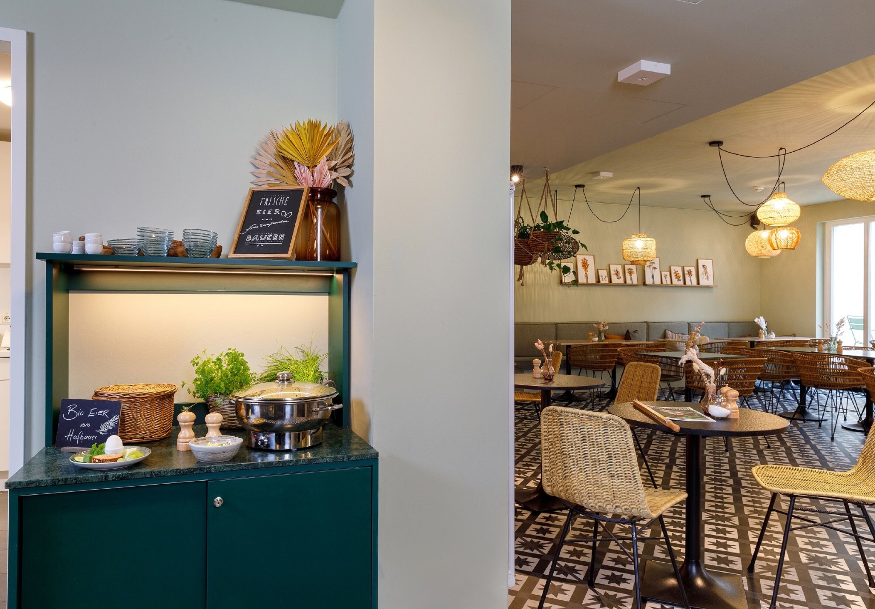 Um restaurante com balcão de buffet, cadeiras de vime e luminárias pendentes.