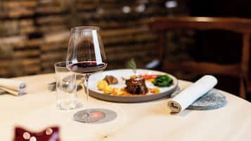 Uma mesa de jantar com um prato de comida, uma taça de vinho e um guardanapo enrolado.