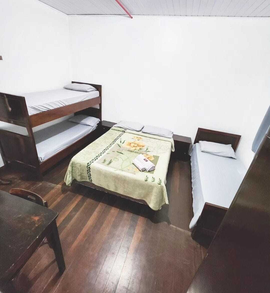Quarto de dormitório com duas beliches, uma mesinha e uma cama simples.