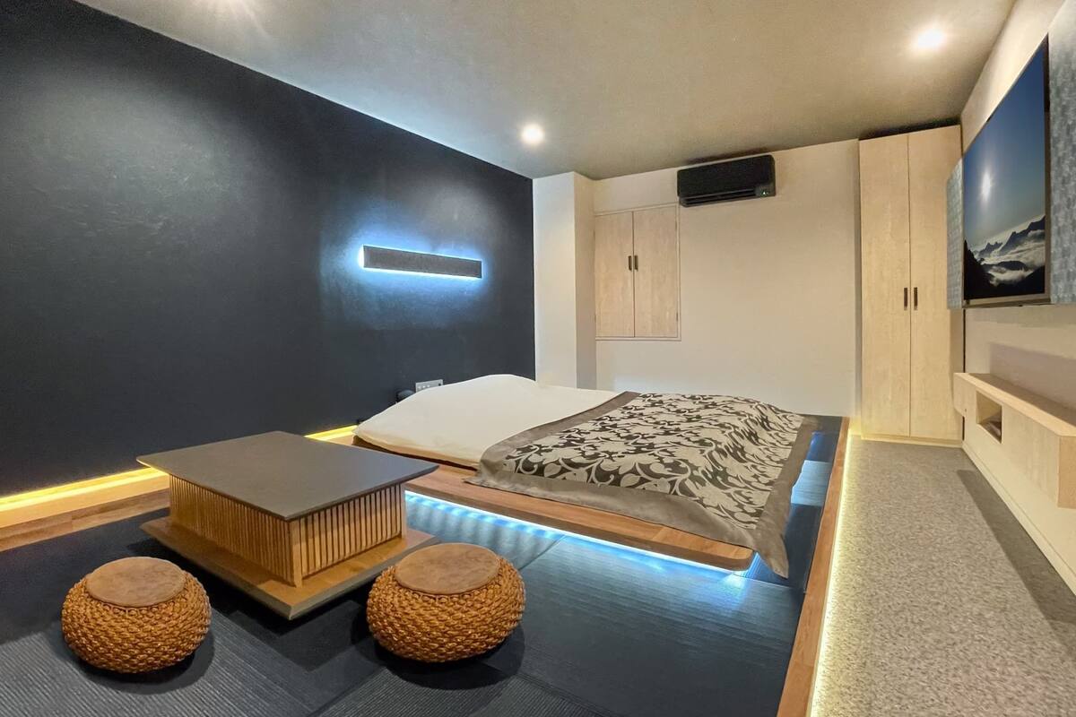 Quarto moderno com cama, mesas de cabeceira, guarda-roupa e ar condicionado de parede.