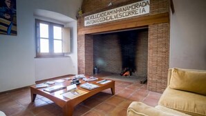 Uma sala de estar com lareira, uma mesa de centro com livros e um sofá.
