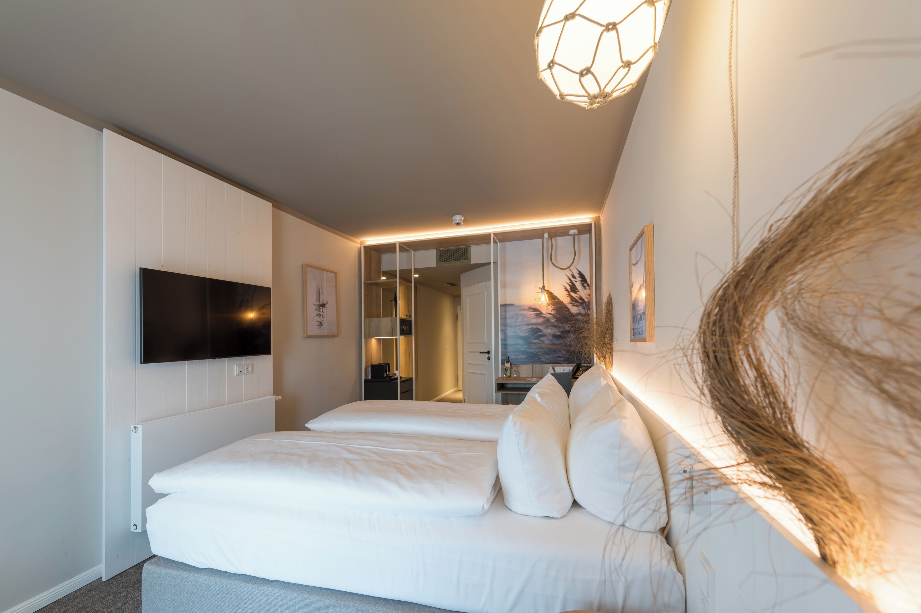 Quarto moderno com uma cama grande, uma TV de tela plana na parede e um lustre no teto.