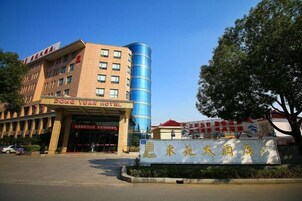 Um hotel com uma entrada imponente, uma grande estrutura cilíndrica azul e uma placa com caracteres chineses.