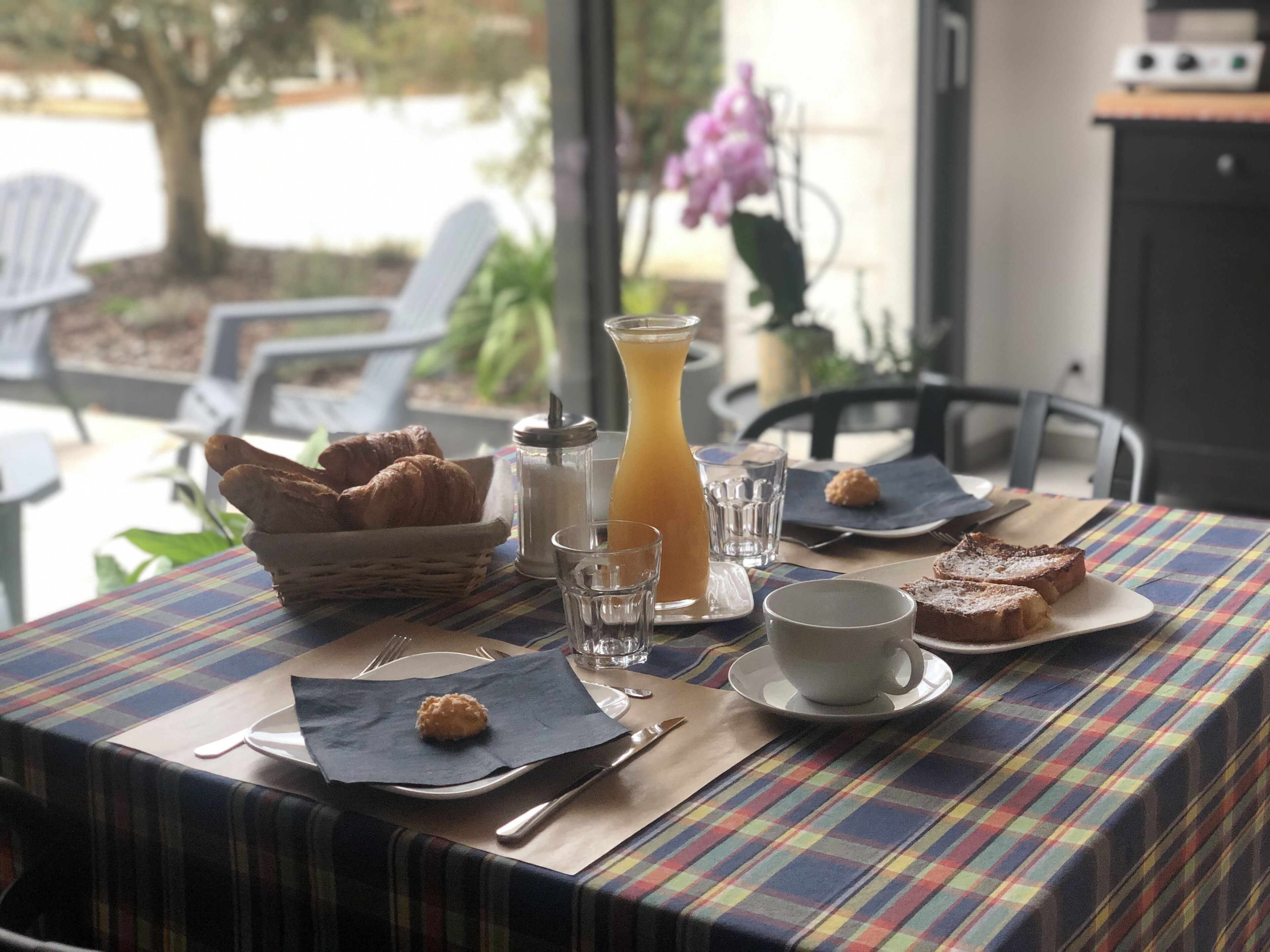 Mesa de café da manhã posta com croissants, um copo de suco de laranja e uma xícara de café.