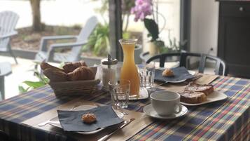 Mesa de café da manhã posta com croissants, um copo de suco de laranja e uma xícara de café.