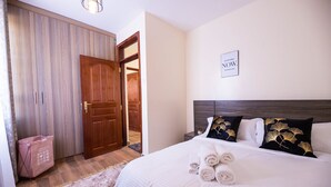 Quarto de hotel com uma cama, um guarda-roupa de madeira, uma porta e uma placa na parede.