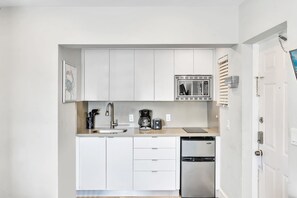 Um micro-ondas, uma placa de cozinha, uma cafeteira/bule 