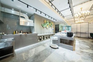 Cozinha moderna com ilha central, eletrodomésticos de aço inoxidável e um candelabro.