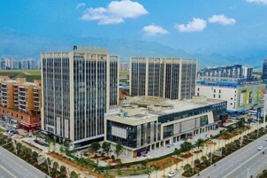 Um complexo moderno de edifícios com várias torres altas, uma praça central aberta e prédios baixos ao redor.
