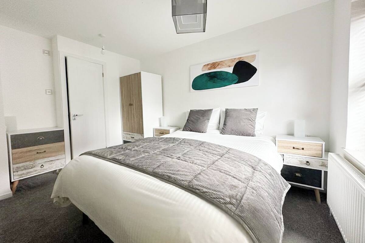 Quarto com cama, mesas de cabeceira, guarda-roupa e um quadro na parede.