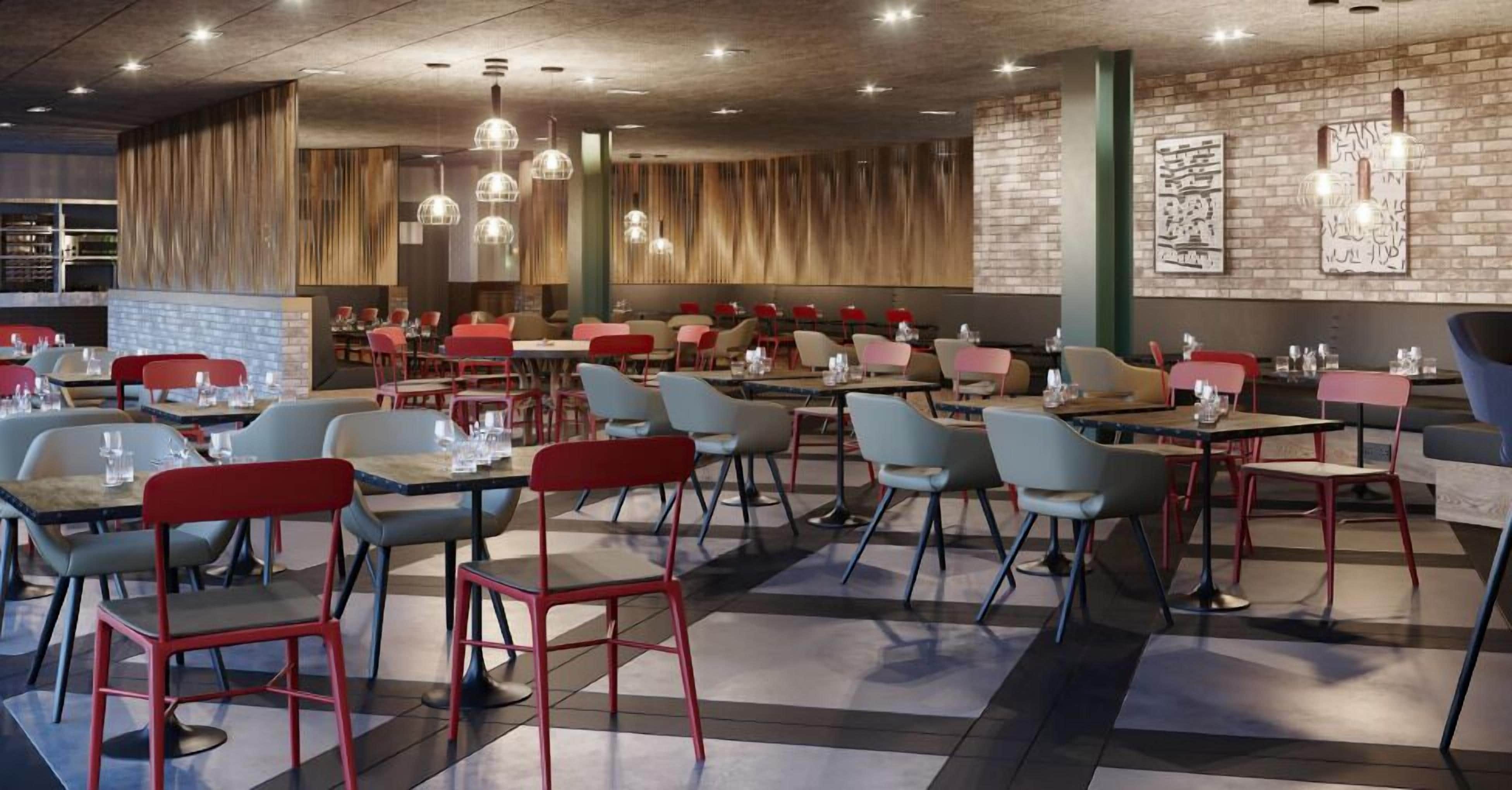 Um restaurante moderno com várias áreas de refeições, cadeiras vermelhas e azuis, e luminárias pendentes.