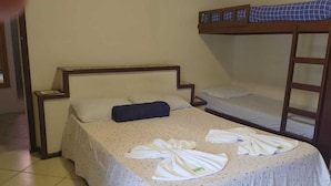 Quarto individual com cama de solteiro e cama de casal, com edredom estampado e toalhas organizadas na cama.