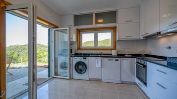 Uma cozinha moderna com máquina de lavar e secar integradas, uma janela grande e vista para o exterior.