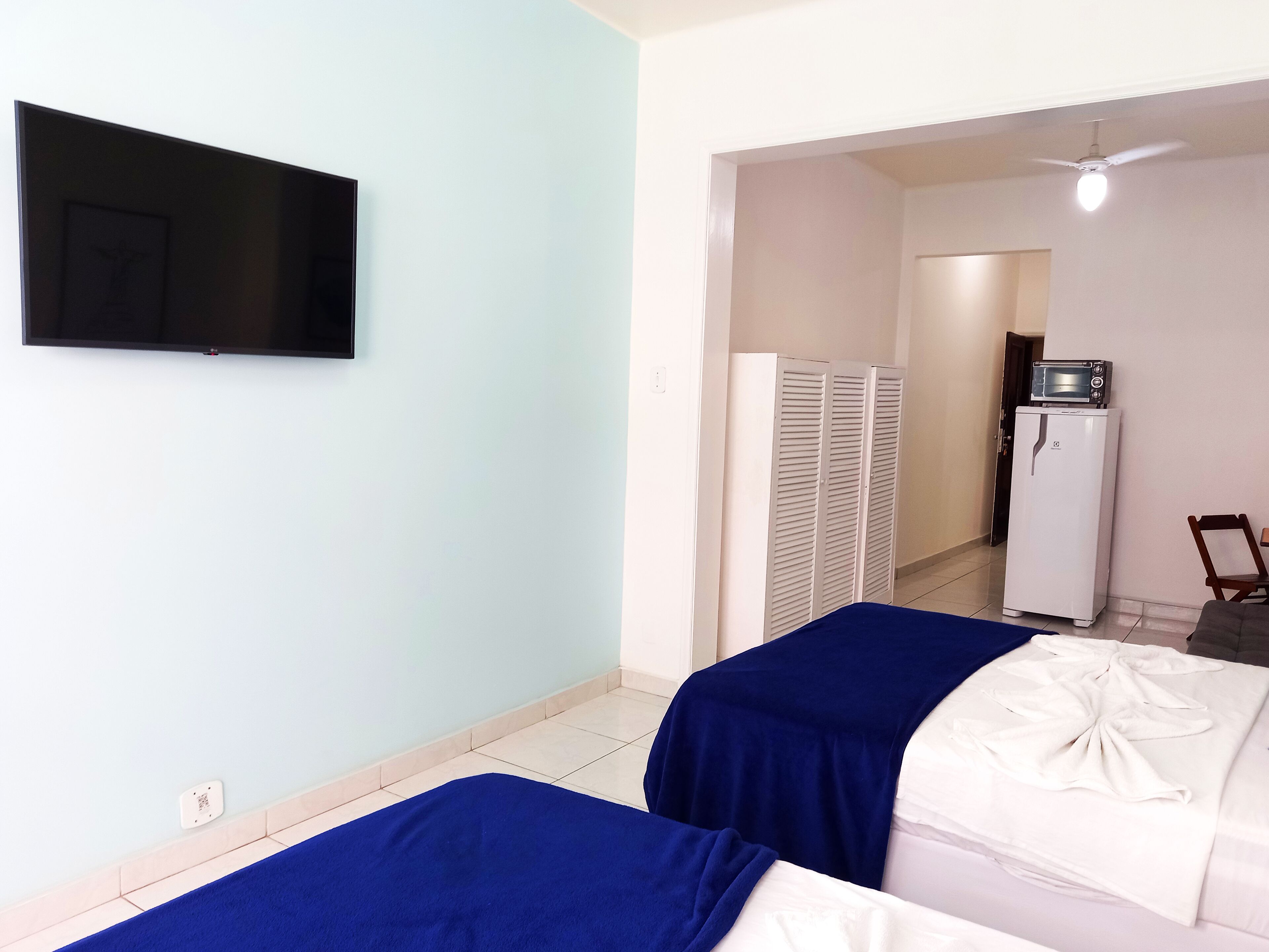 Quarto de hotel com duas camas, televisão, micro-ondas e frigorífico.