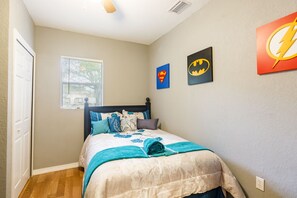 Quarto com cama, janela e obras de arte nas paredes.