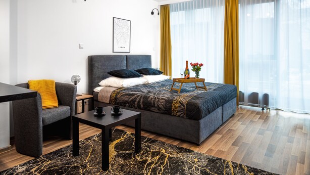 Quarto de hotel moderno com uma cama grande, um sofá, uma mesa de centro e um mapa na parede.