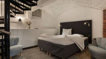 Quarto moderno com uma cama grande, cabeceira preta, escada e parede de tijolos.