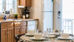 Uma cozinha com armários de madeira, uma geladeira branca e uma mesa de jantar posta com pratos e copos brancos.