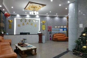 Um saguão de hotel com balcão de recepção, área de estar e detalhes decorativos.