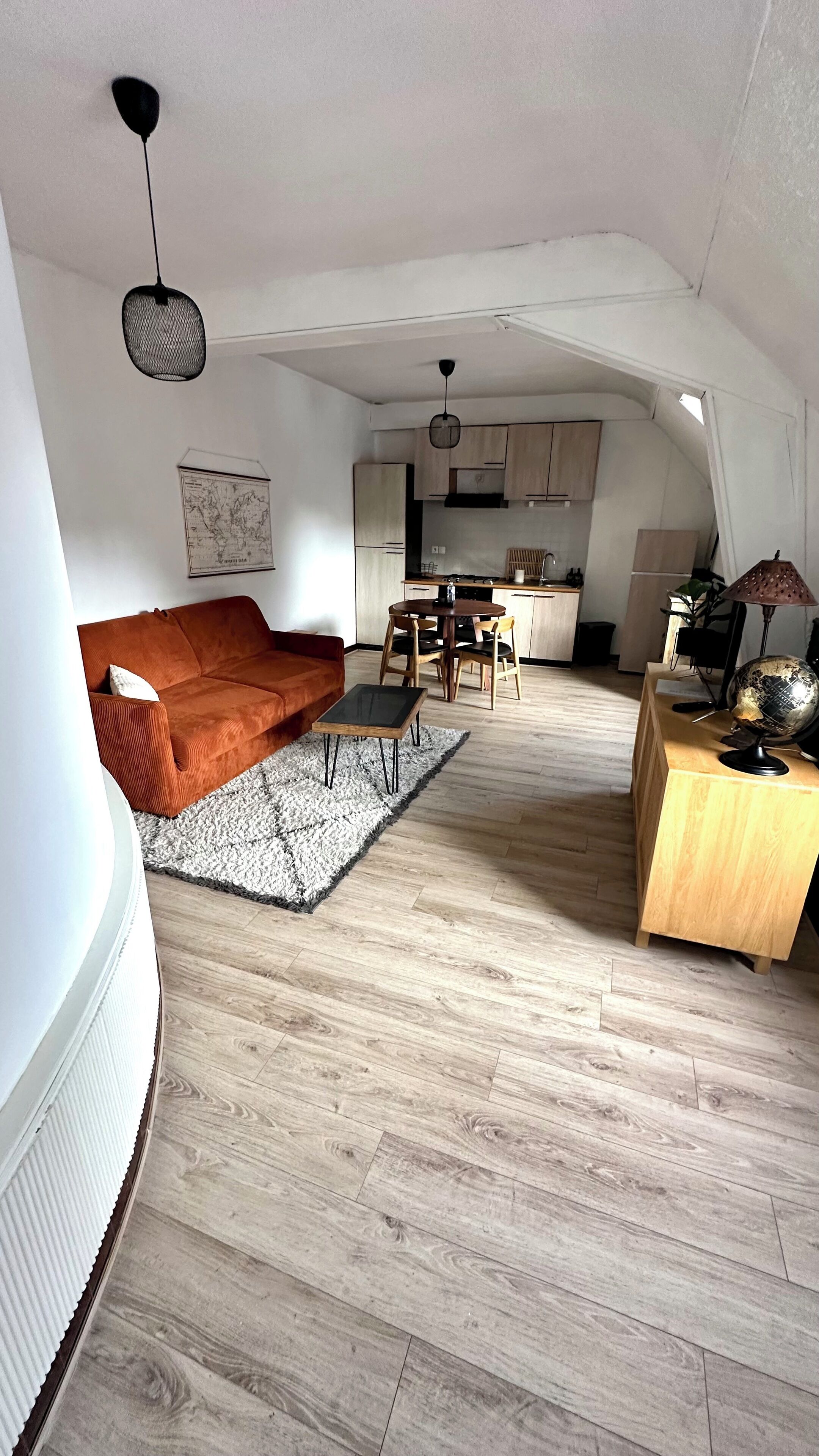 Um loft espaçoso com pé direito alto, uma sala de estar aconchegante com sofá e mesa de centro, uma área de jantar com mesa e cadeiras, e uma cozinha com armários de madeira.
