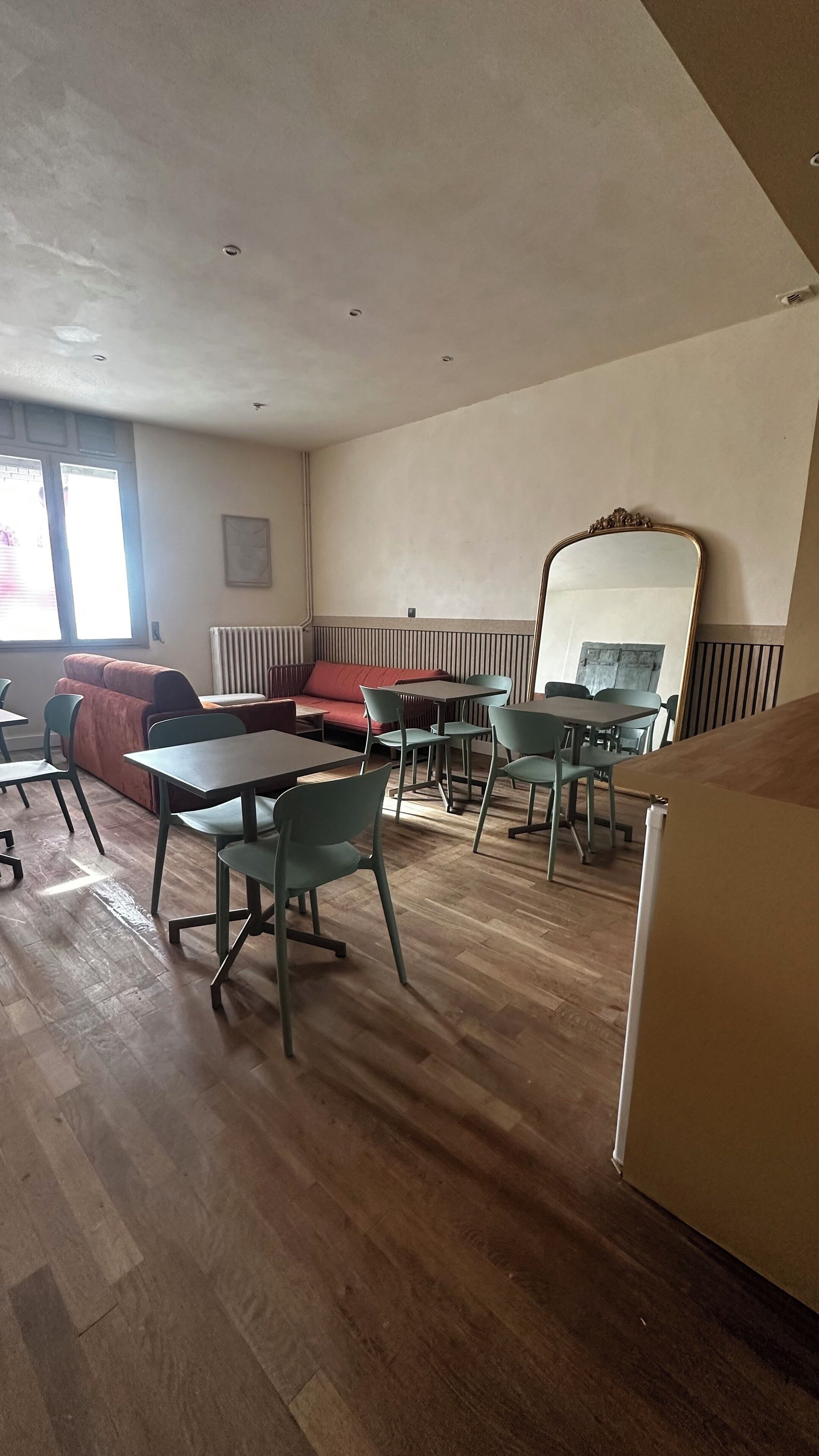 Quarto com sofá, mesas de jantar, cadeiras e radiador.