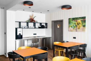 Quarto de hotel moderno com área de refeições, cozinha e uma grande janela com vista para o exterior.
