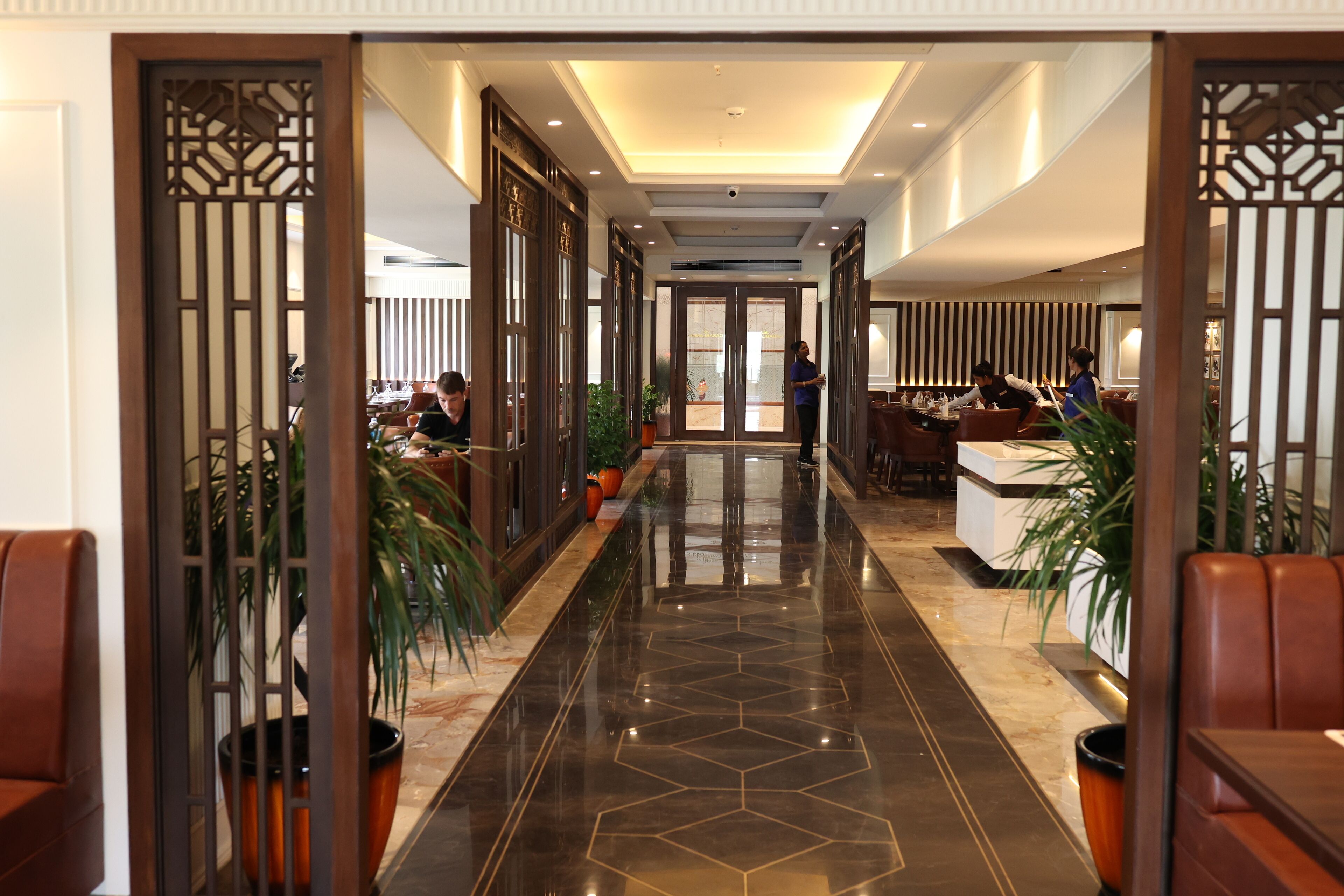 Um hall de hotel com piso de mármore polido, painéis de madeira e áreas de estar.