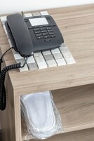 Uma mesa com um telefone, um teclado e um objeto embalado em plástico por baixo.