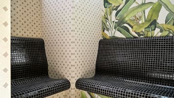 Canto de um quarto com papel de parede estampado e um mural de folhas verdes.