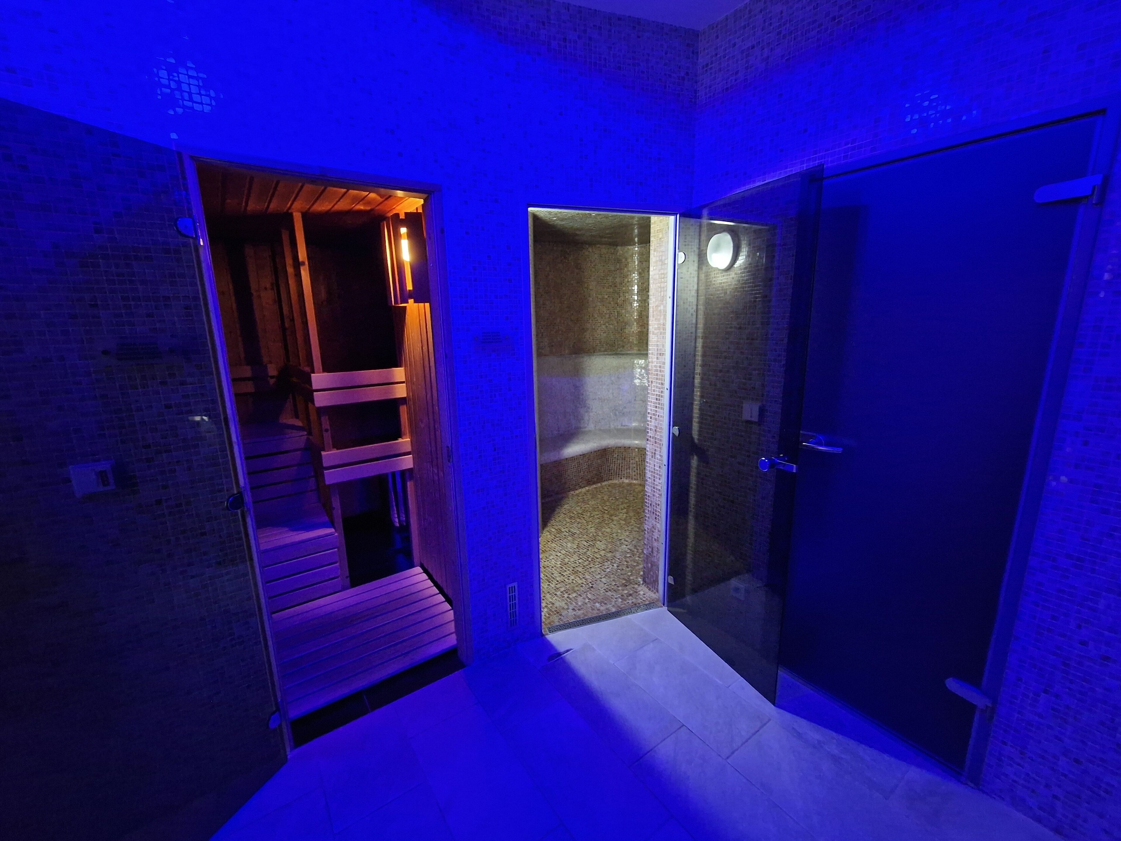 Um banheiro moderno com box de vidro, um banco de madeira e piso revestido de azulejos.
