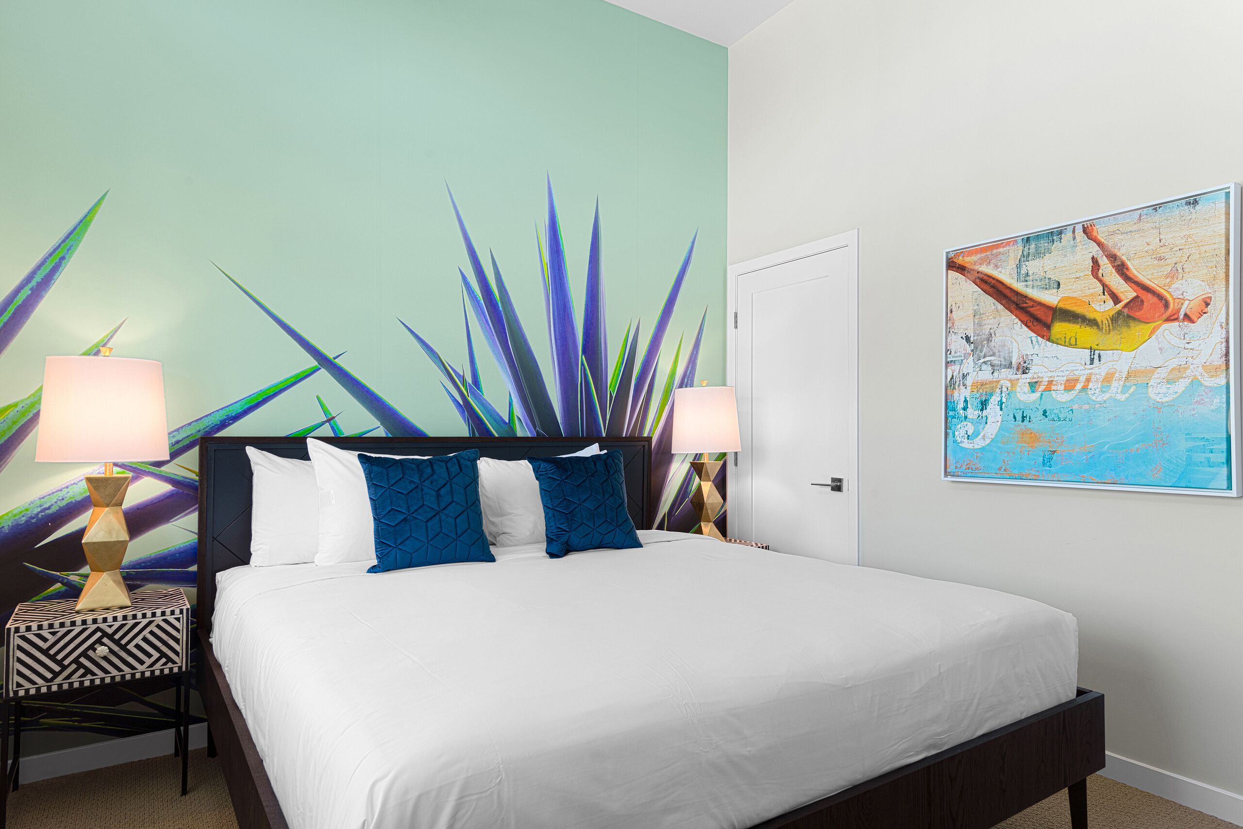 Cama bem arrumada com lençóis brancos, cabeceira escura e duas almofadas decorativas.