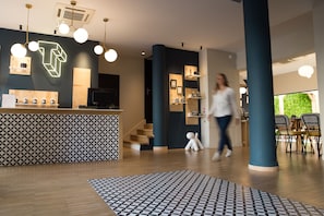 Uma área de recepção moderna com parede de padrão geométrico, balcão de atendimento e escada para andares superiores.