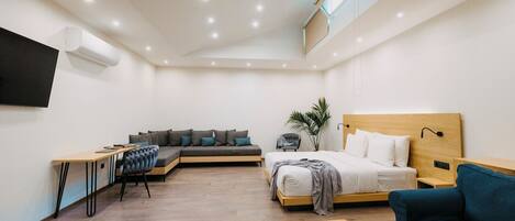 Quarto moderno e bem iluminado, com cama, sofá, escrivaninha e cadeira.