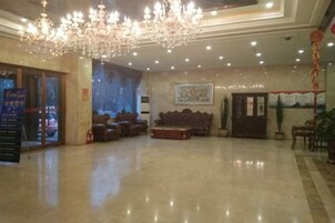Um hall amplo com lustre, área de estar e balcão de recepção.