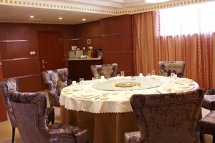 Mesa de jantar redonda com toalha branca, rodeada por cadeiras estofadas.