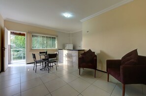 Uma sala de estar ampla com uma mesa de jantar, duas cadeiras, um sofá e uma geladeira.