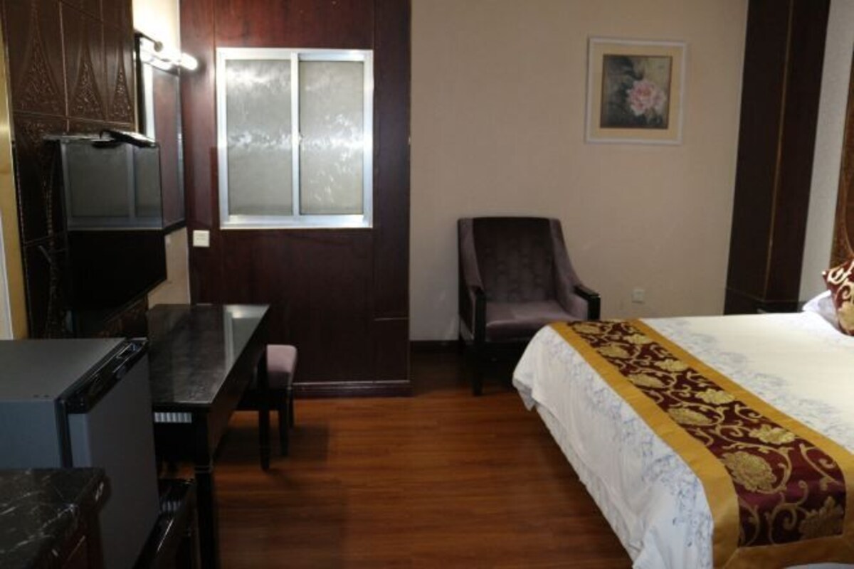 Quarto de hotel com uma cama, uma escrivaninha, uma cadeira e uma televisão.